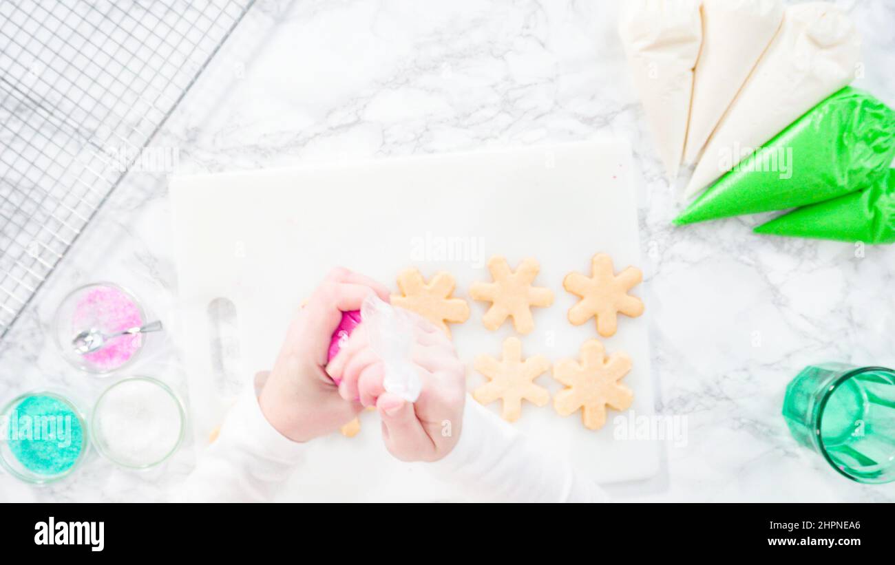 Flat lay. Stp by step. Icing snowflake shaped sugar cookies with pink ...