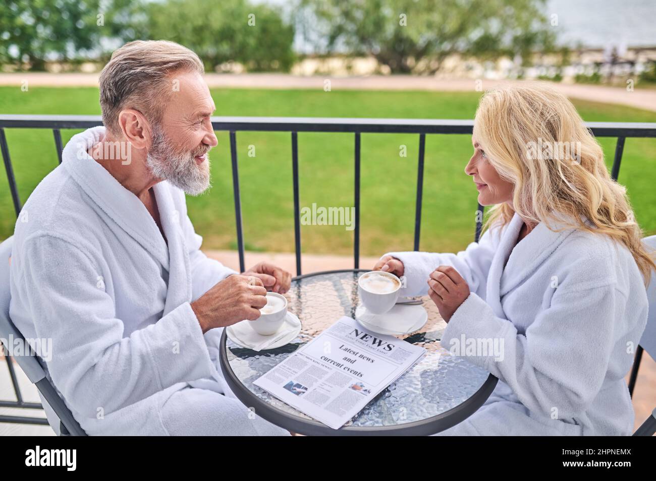 A couple in whote robes having morning coffee at the balcony Stock ...