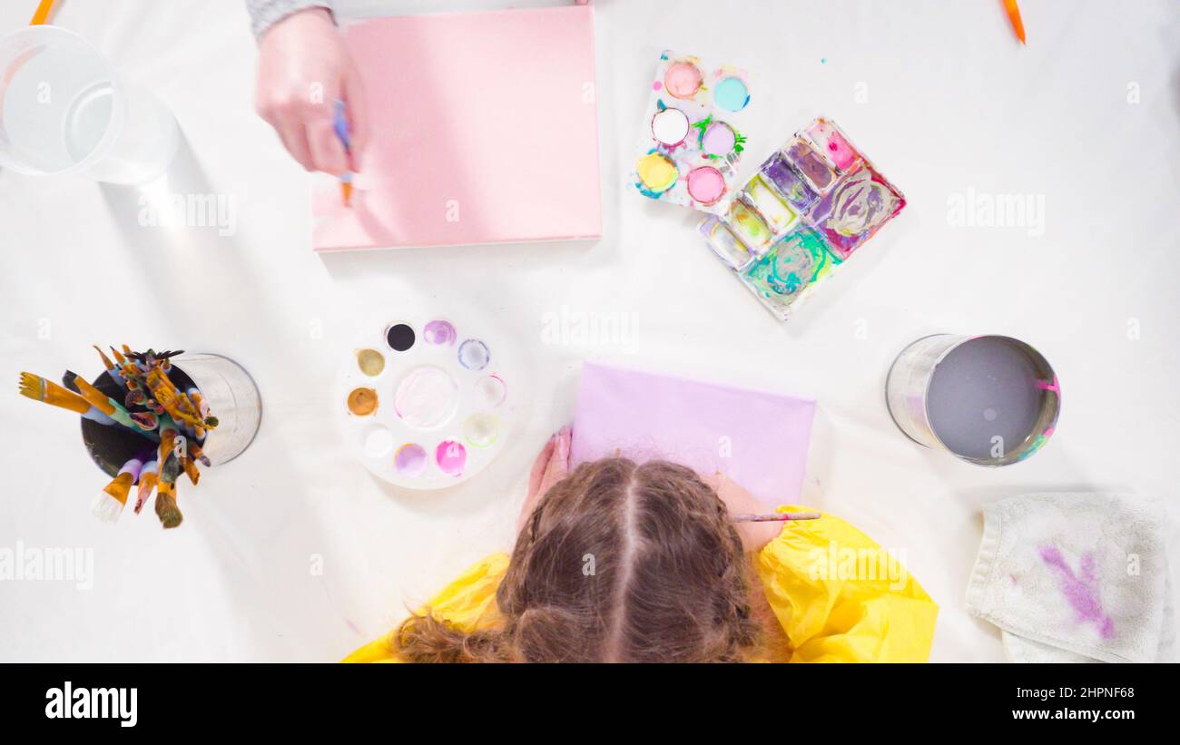 Flat lay. Little girl painting with acrylic paint on canvas with her ...