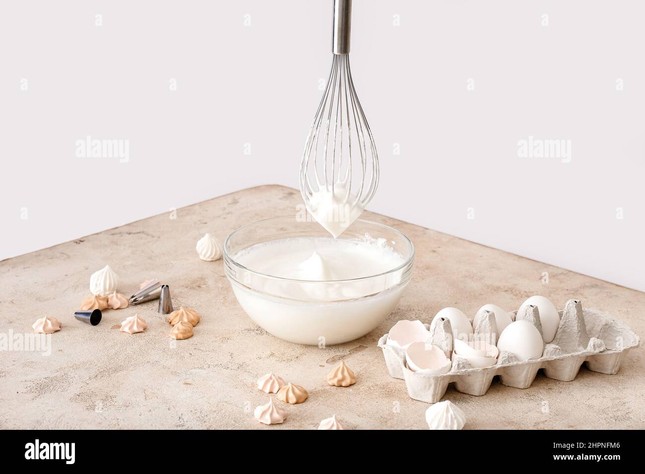 Whisk with meringue and chicken eggs on table Stock Photo - Alamy