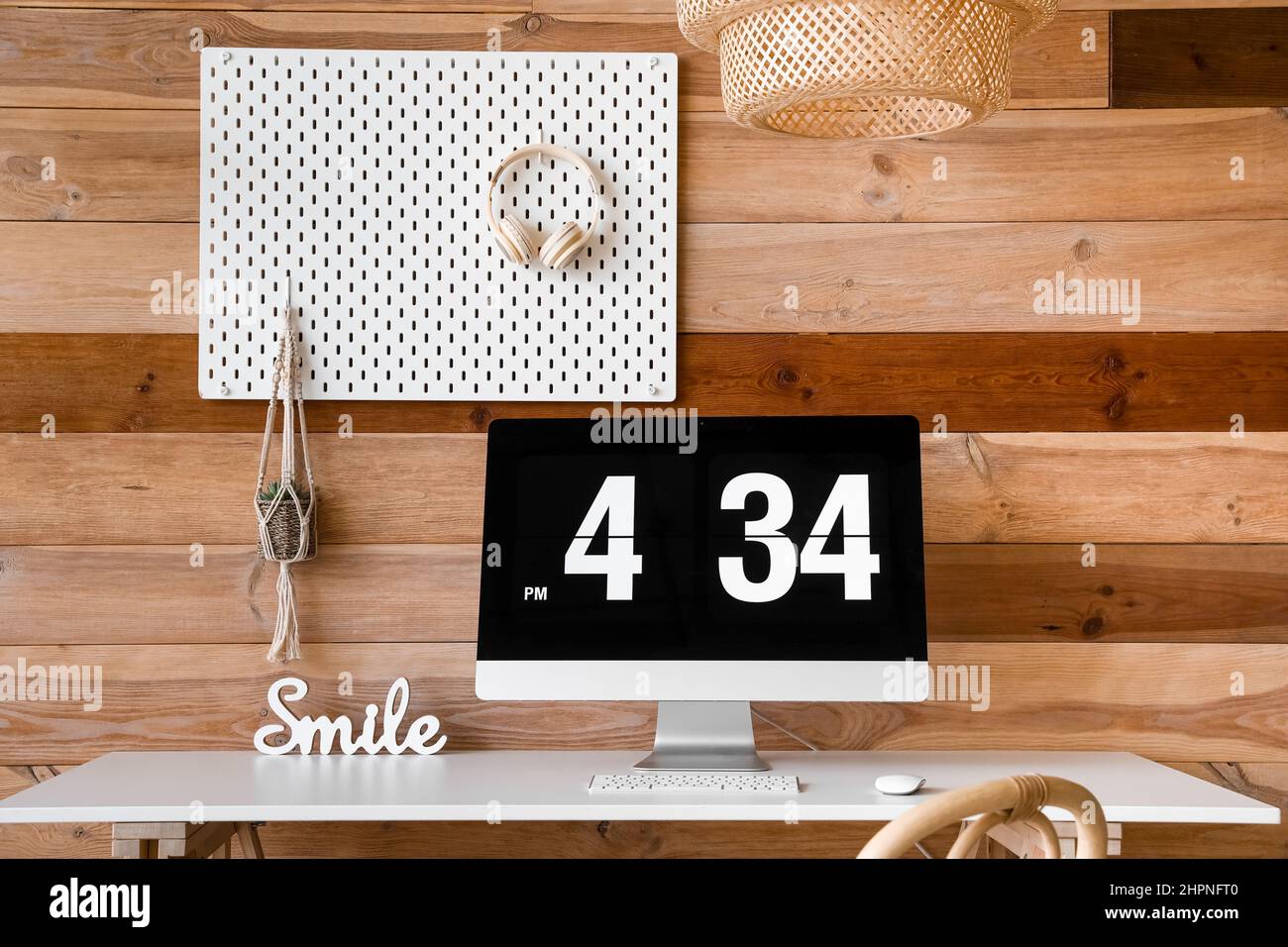 Modern workplace with computer and peg board hanging on wooden wall ...
