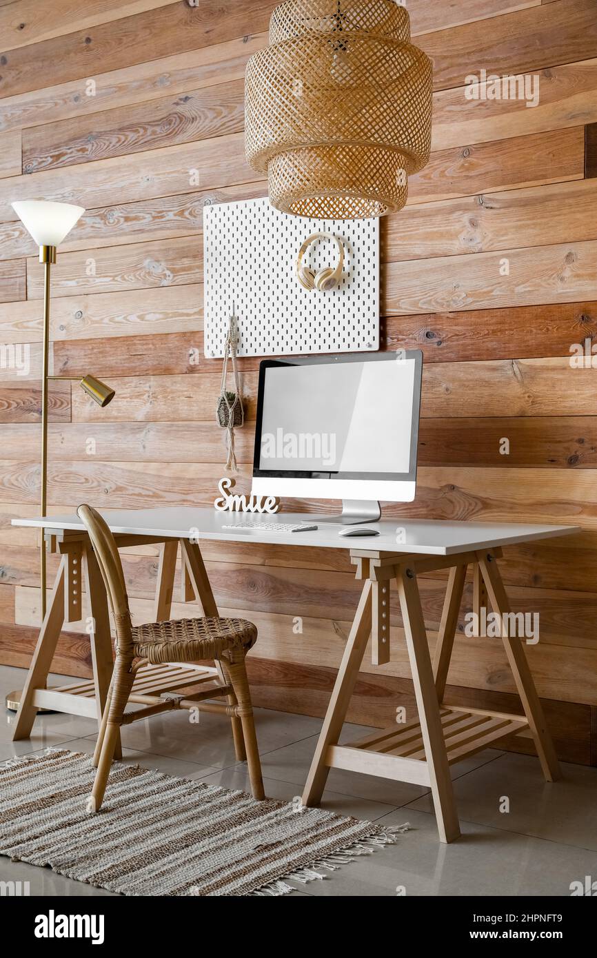 Modern workplace with computer and peg board hanging on wooden wall ...