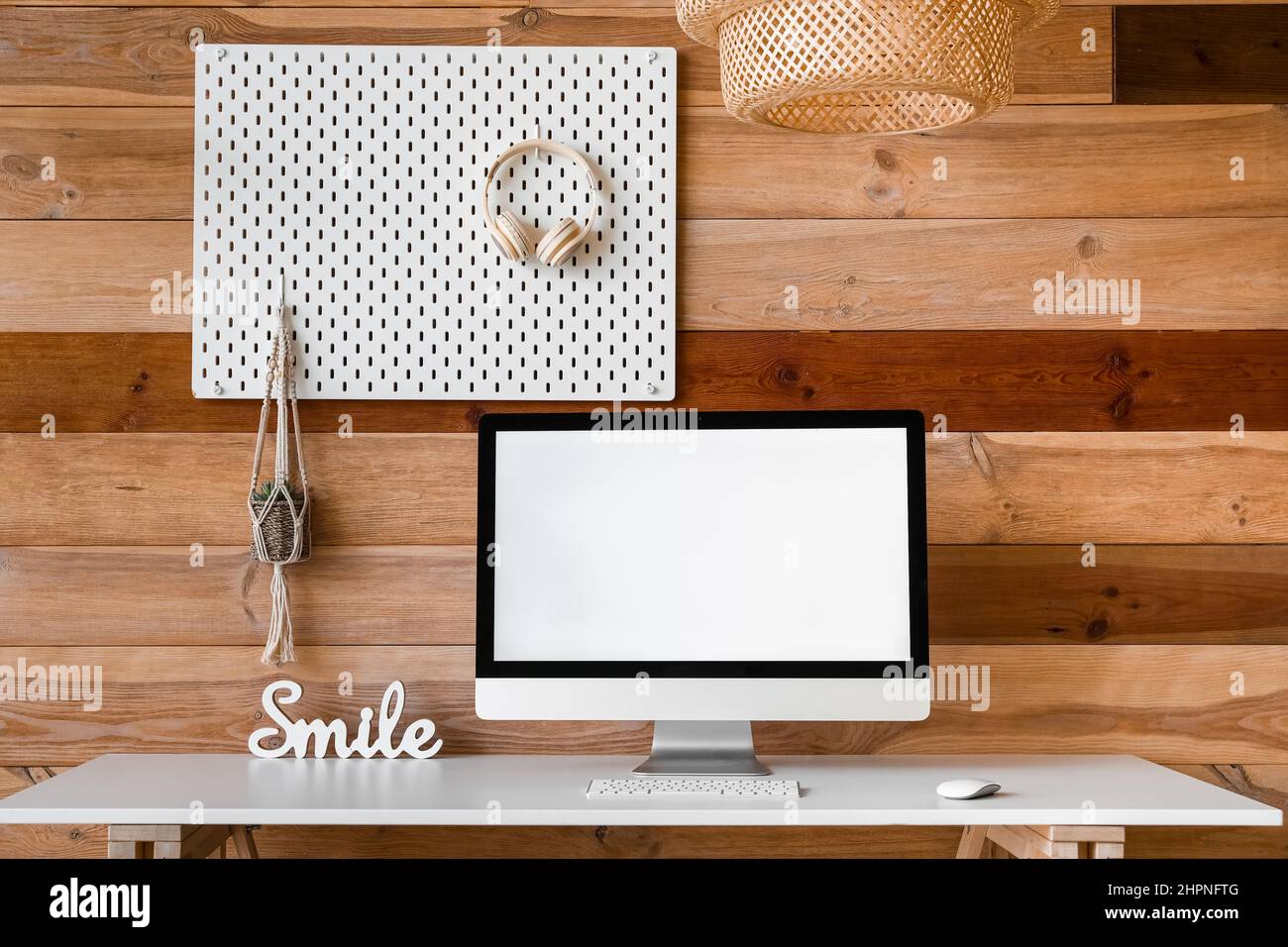 Modern workplace with computer and peg board hanging on wooden wall ...