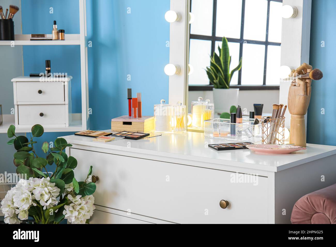 Stylish workplace of makeup artist with decorative cosmetics near blue ...