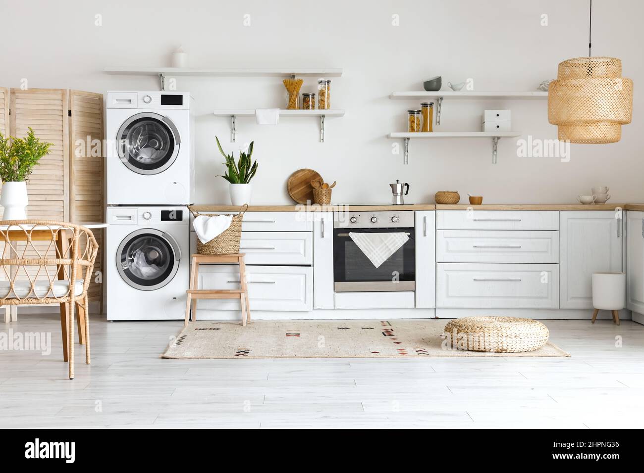 Interior of light kitchen with washing machines, white counters and ...