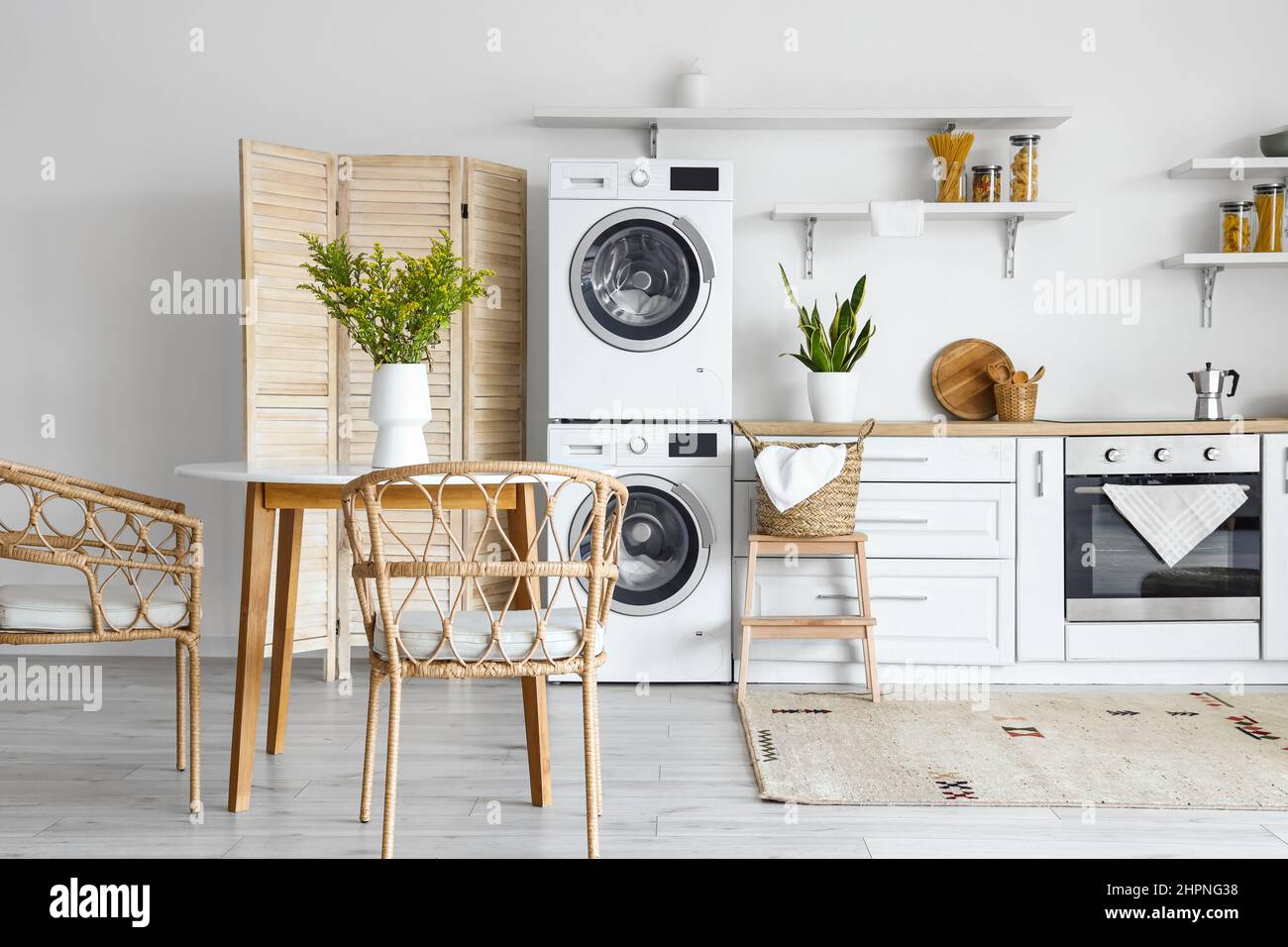 Interior of light kitchen with washing machines, white counter and ...