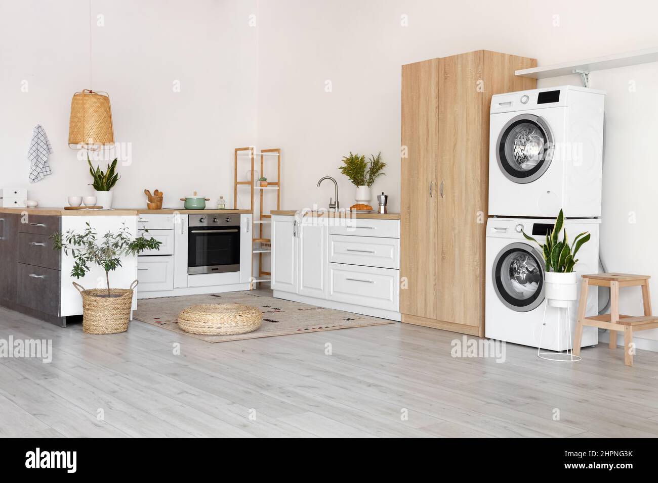 Interior of light kitchen with washing machines, white counters and ...