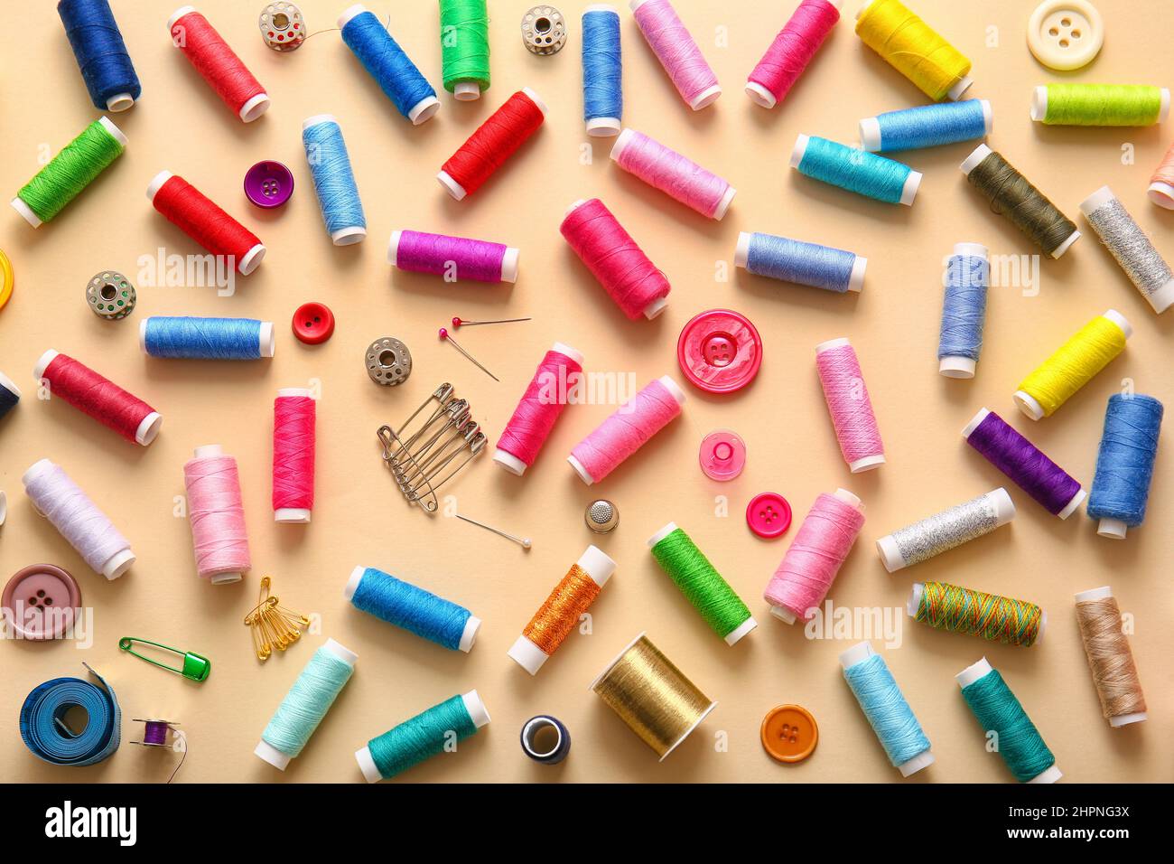 Thread spools with buttons and pins on beige background Stock Photo - Alamy