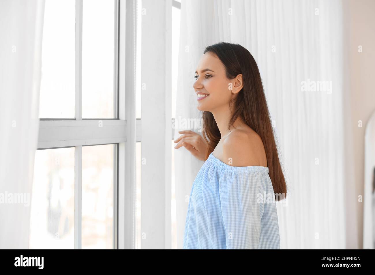 Pretty young woman near window Stock Photo - Alamy
