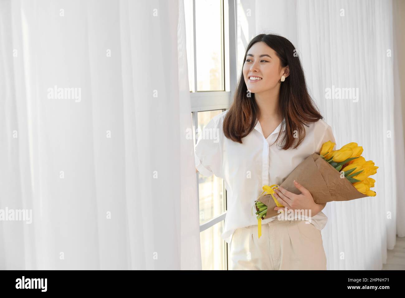 Pretty young Asian woman with bouquet of flowers near window Stock ...