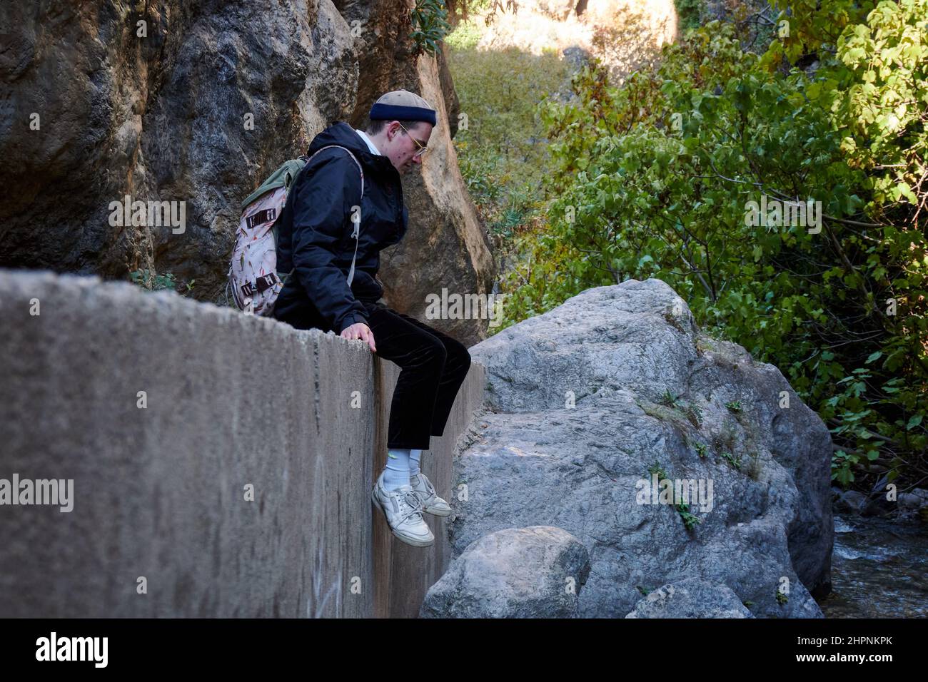 Side view of a male hiker sitting on the edge of the walking trail in ...