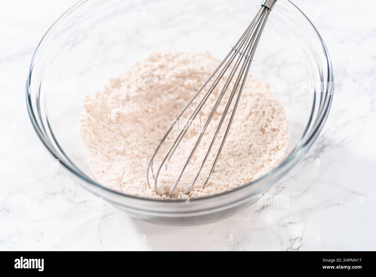 Mixing dry ingredients in a large glass mixing bowl to bake soft ...