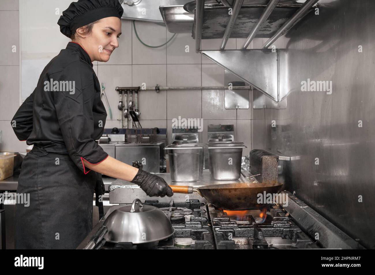 Side view of female chef working in commercial kitchen. High quality ...