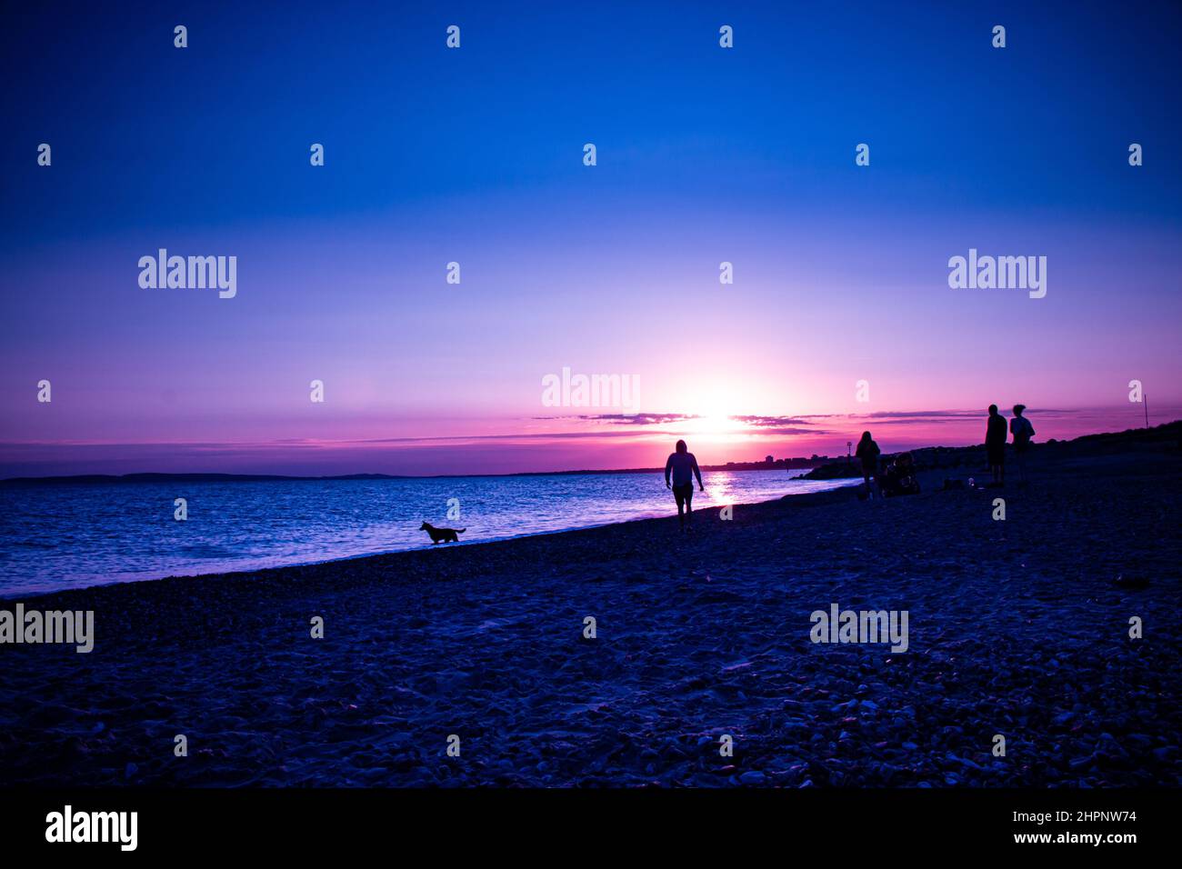 Beautiful shot purple beach scene and people silhouettes at sunset ...