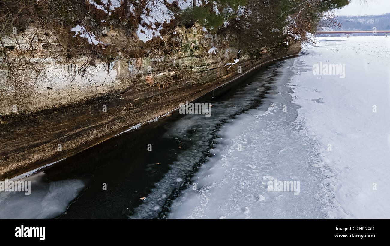 Roots, grass, and snow fall over ledge into river Stock Photo - Alamy