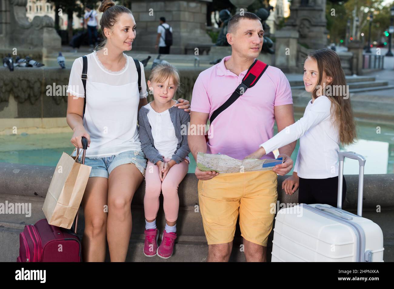 parents with two kids traveling together searching location on paper ...