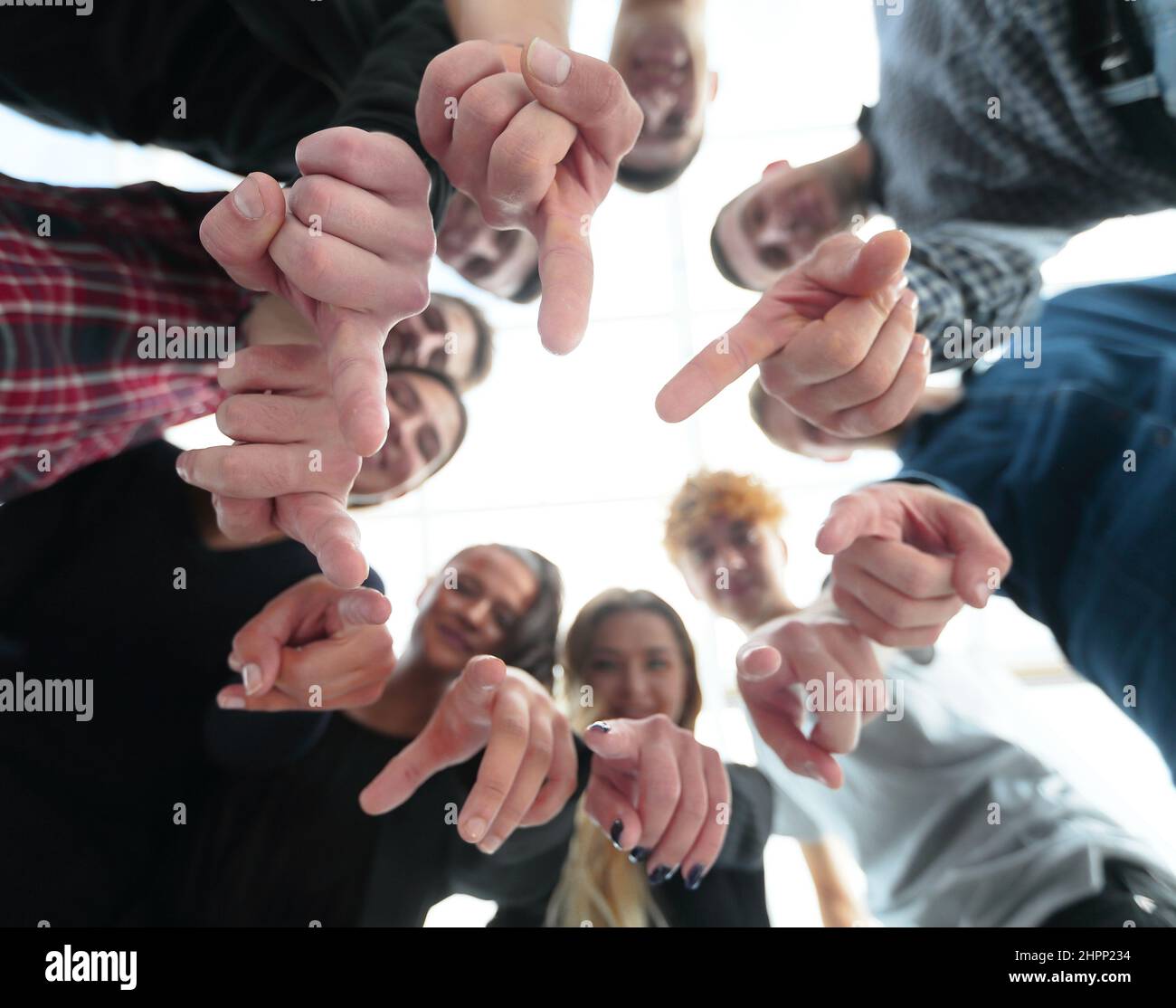 bottom view. ambitious young people standing in a circle and pointing ...