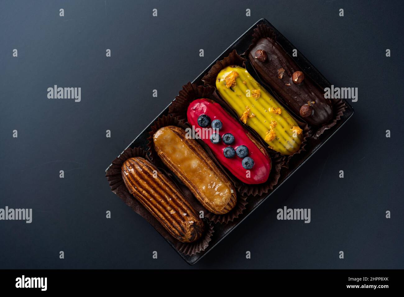 colorful eclairs on a black plate on a black background top view Stock ...