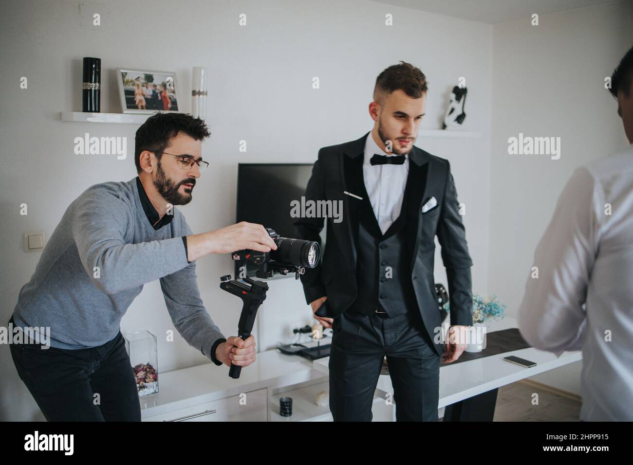 Cameraman filming an event with a young man wearing black suit standing ...