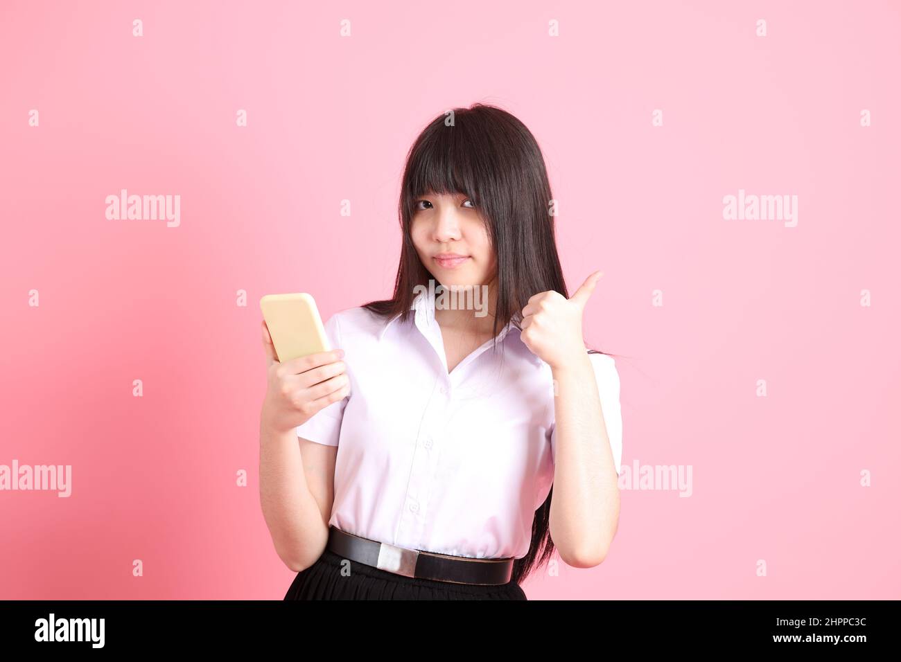 The teen Asian girl with university uniform standing on the pink ...