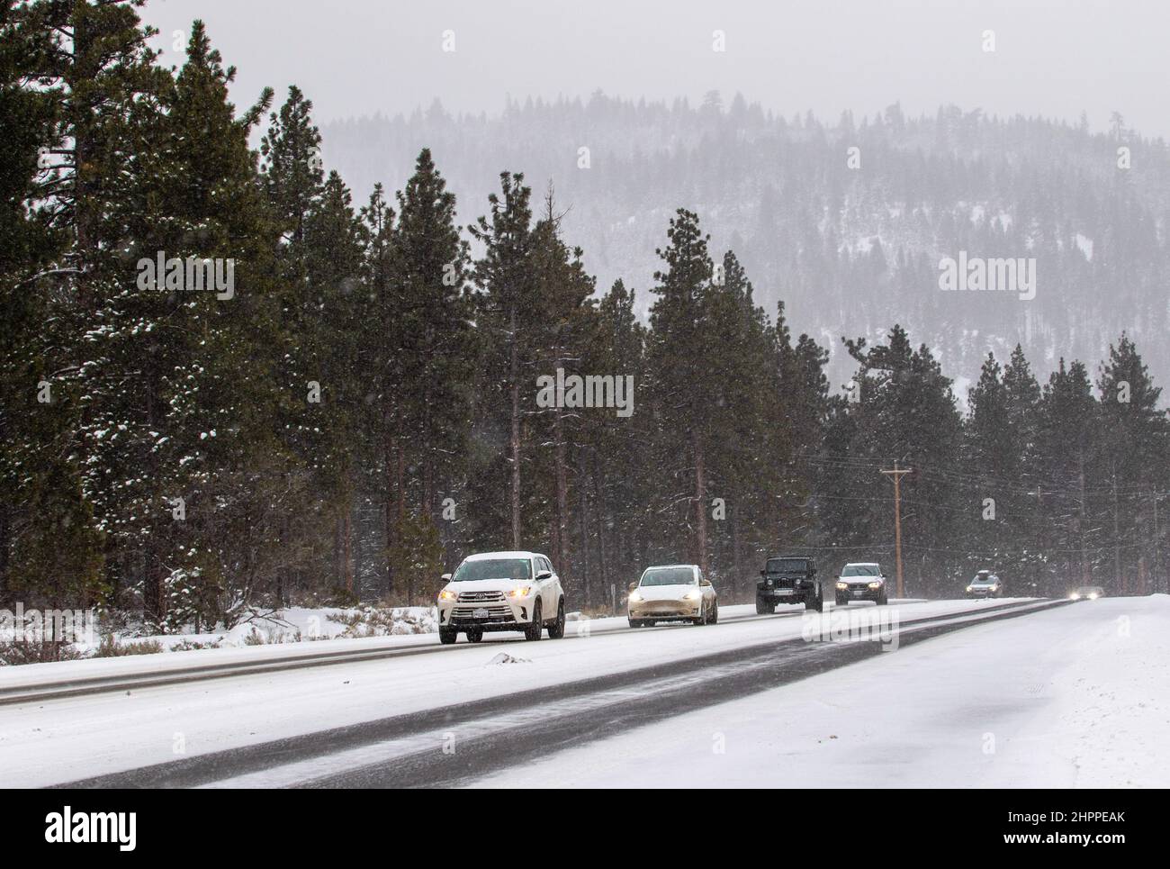 Cars descend a mountain road in winter weather. Winter road conditions ...