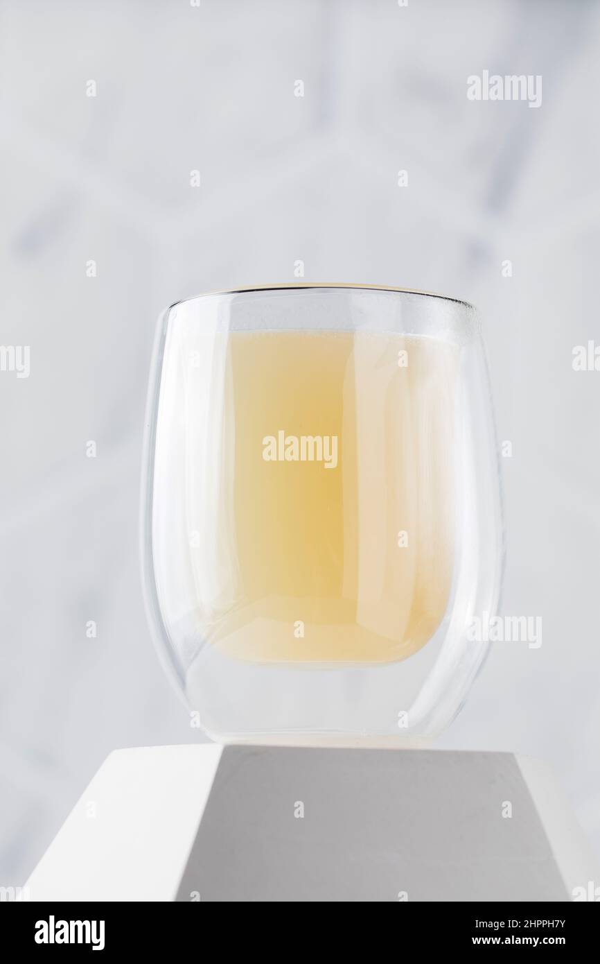 Healthy bone broth in a transparent mug on a pedestal on a light ...