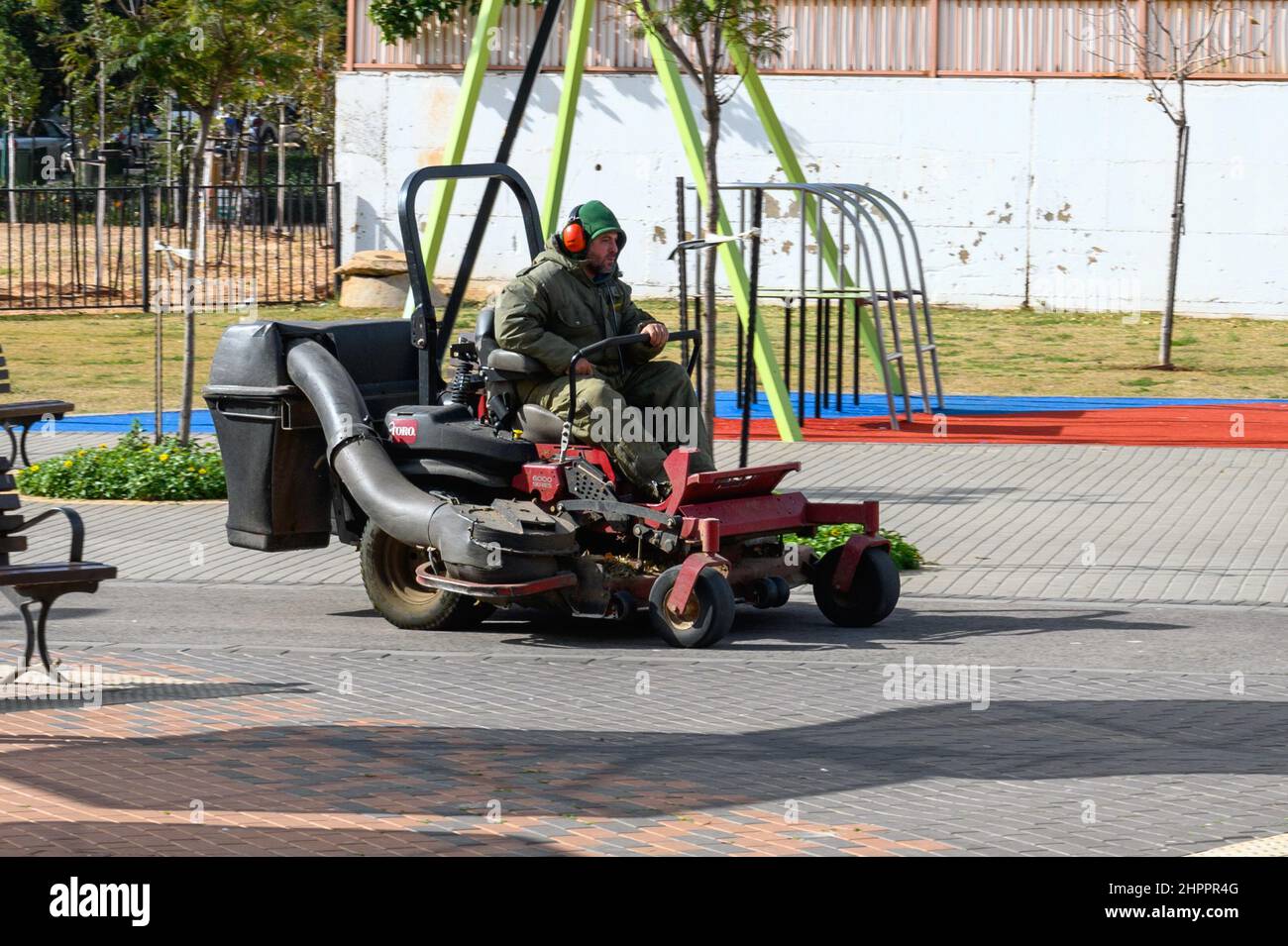 Netanya, Israel - February 8, 2022: A cleaner on a tractor with a lawn ...