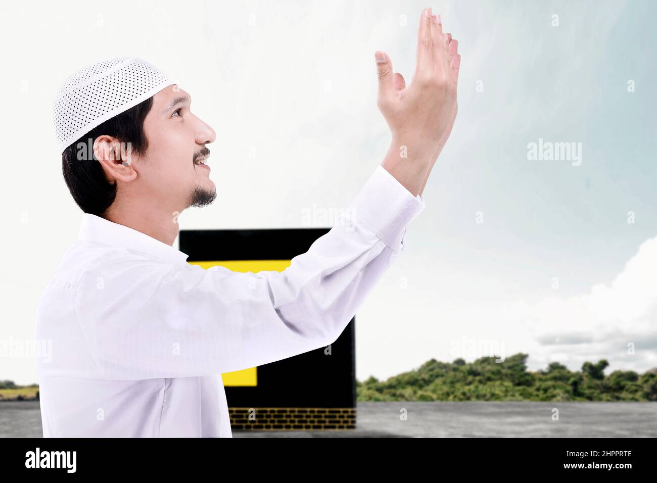 Asian Muslim man standing and praying with Kaaba view and blue sky ...