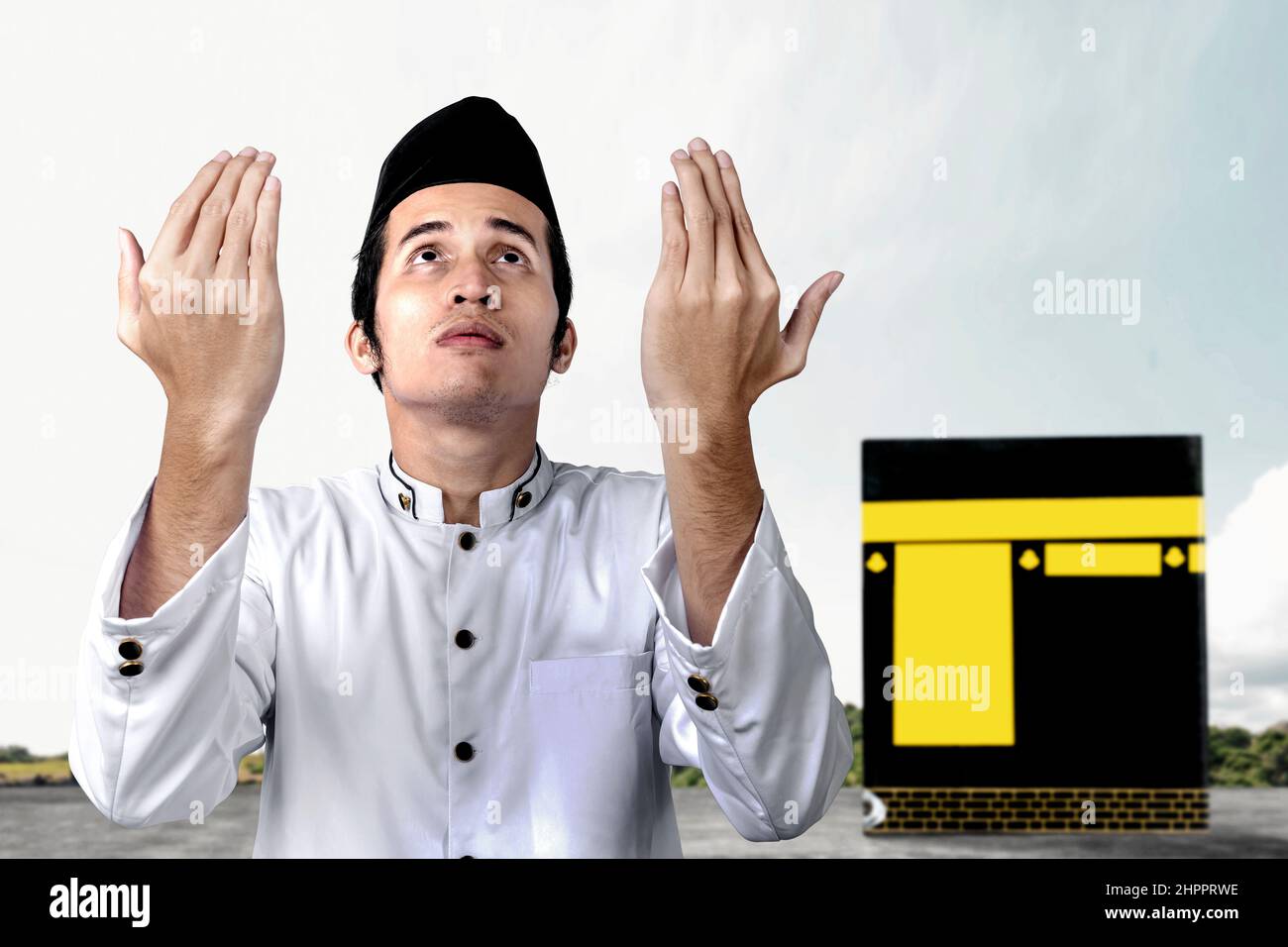 Asian Muslim man standing and praying with Kaaba view and blue sky ...