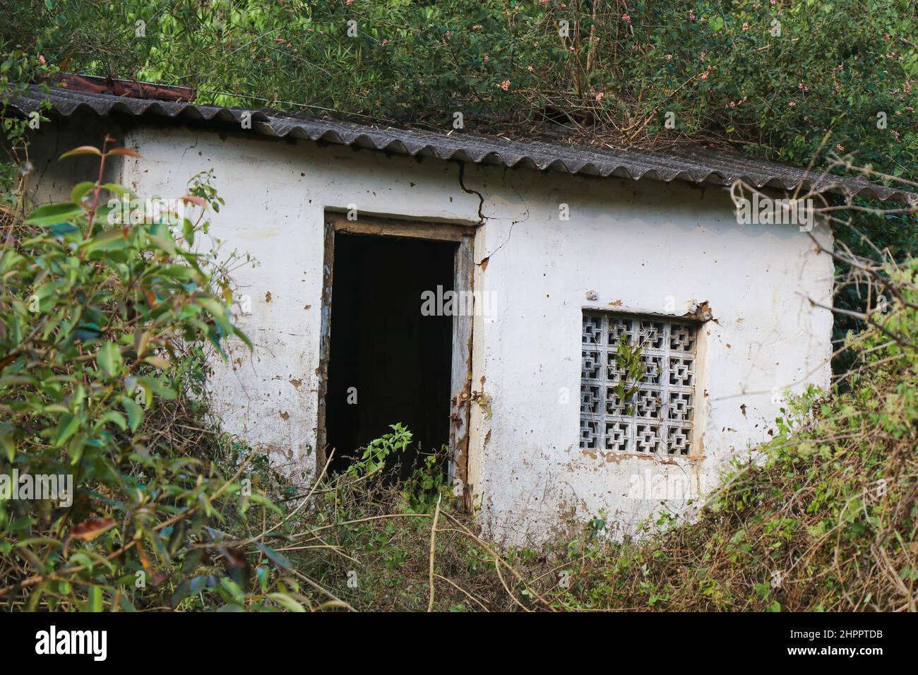 The exterior of a small abandoned house without doors surrounded by ...
