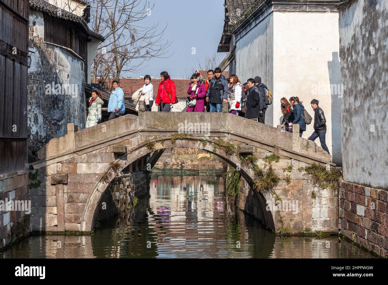 Group of tourists crossing a stone bridge spanning a canal in the water ...