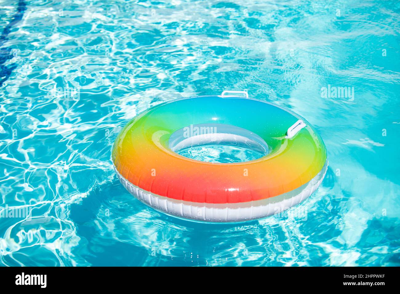 Blue aqua background. Pool float, rainbow ring floating in a refreshing ...