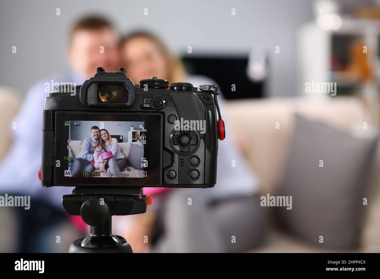 Camera stand on tripod with picture preview on screen, family posing on ...