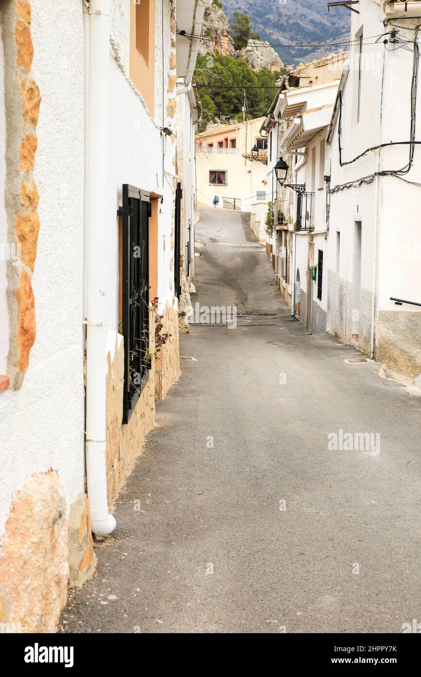 Whitewashed facades and narrow street in Abdet village, Alicante, Spain ...