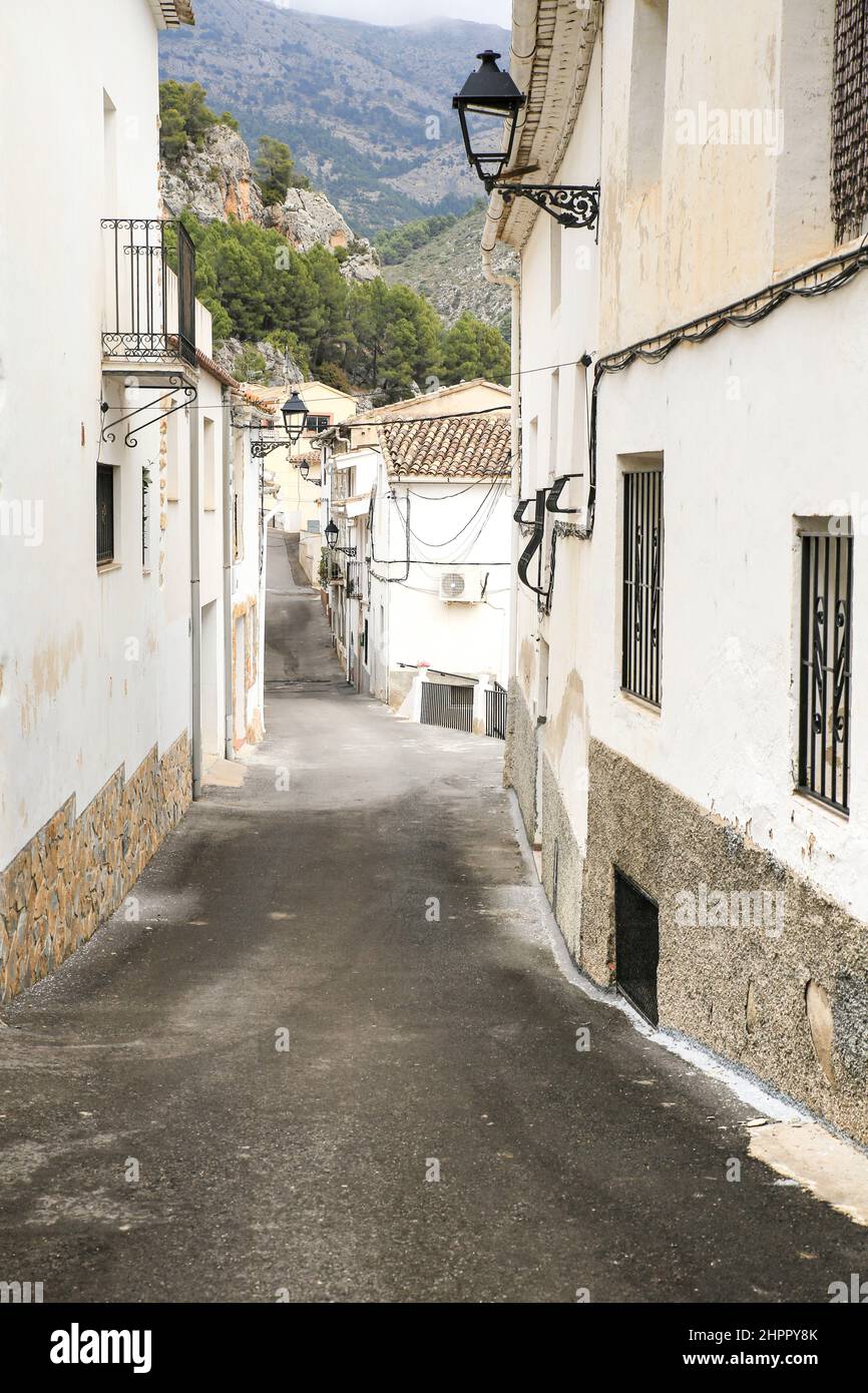 Whitewashed facades and narrow street in Abdet village, Alicante, Spain ...