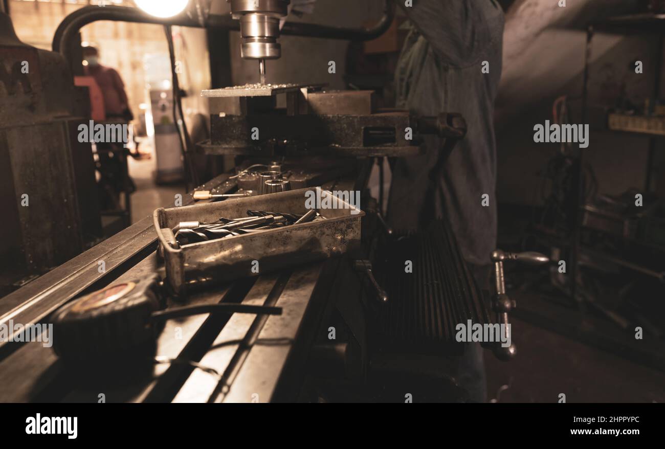 Tools in plastic box on blur milling machine and worker in workshop ...