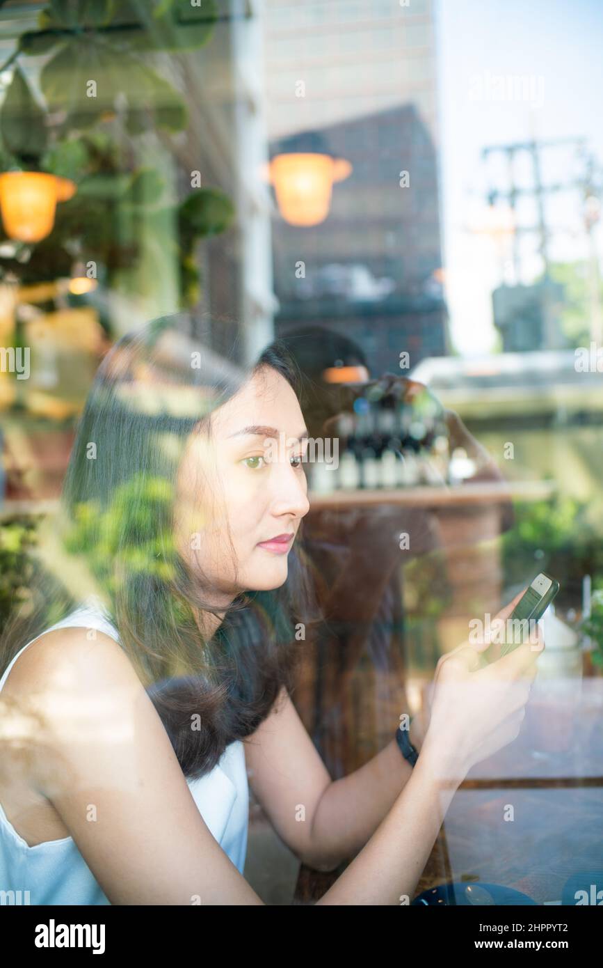 Beautiful asian women sitting in urban coffee shop looking out of ...