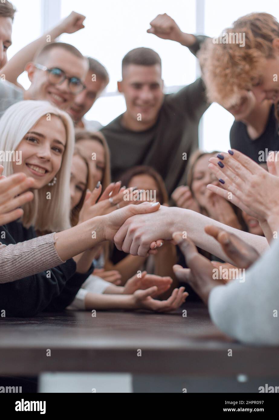 close up. handshake of young people to the applause of their friends ...
