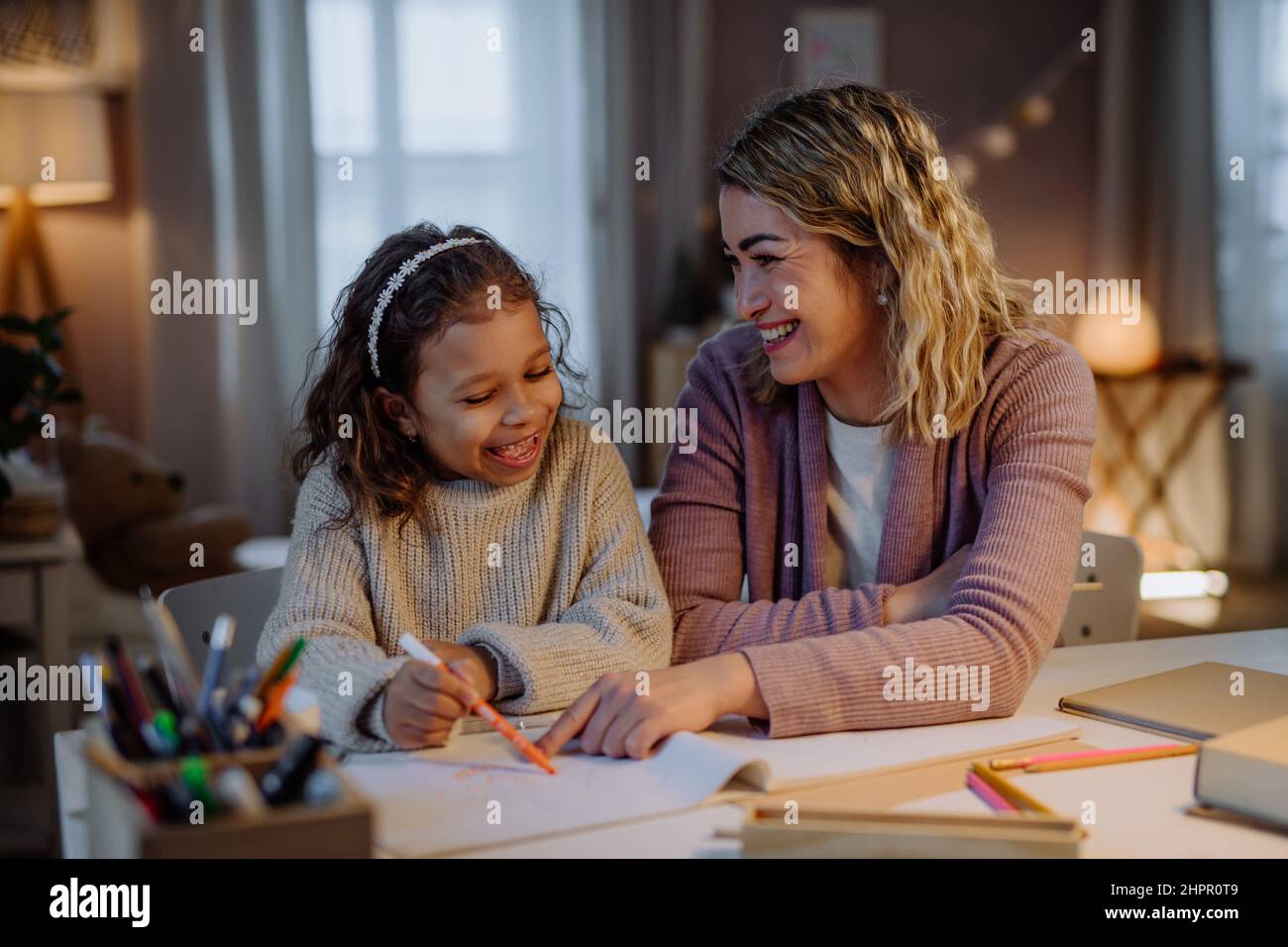 Little girl doing homework with her mother in evening at home Stock ...