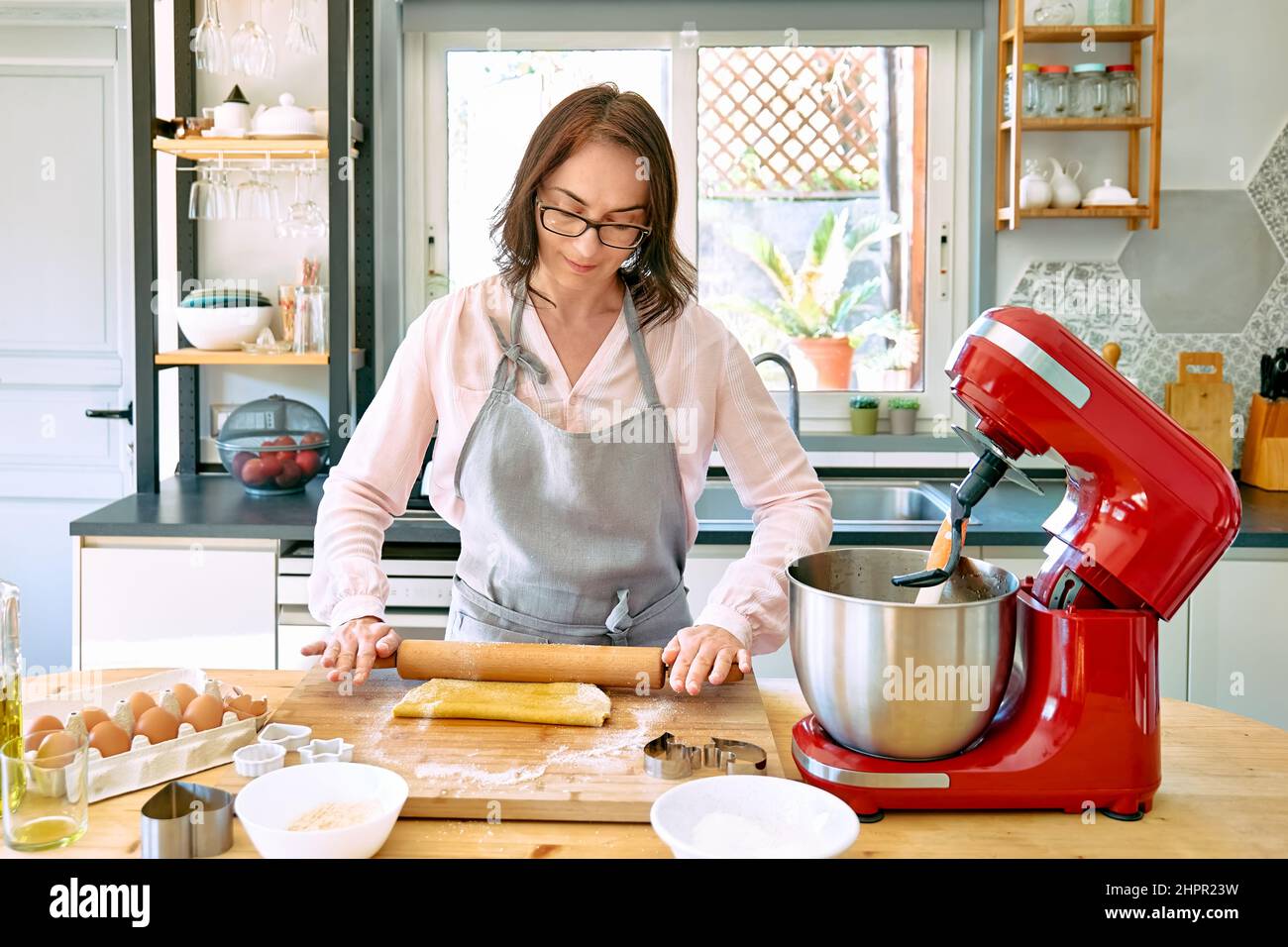 Woman wearing apron baking cookies in cozy kitchen. Housewife ...