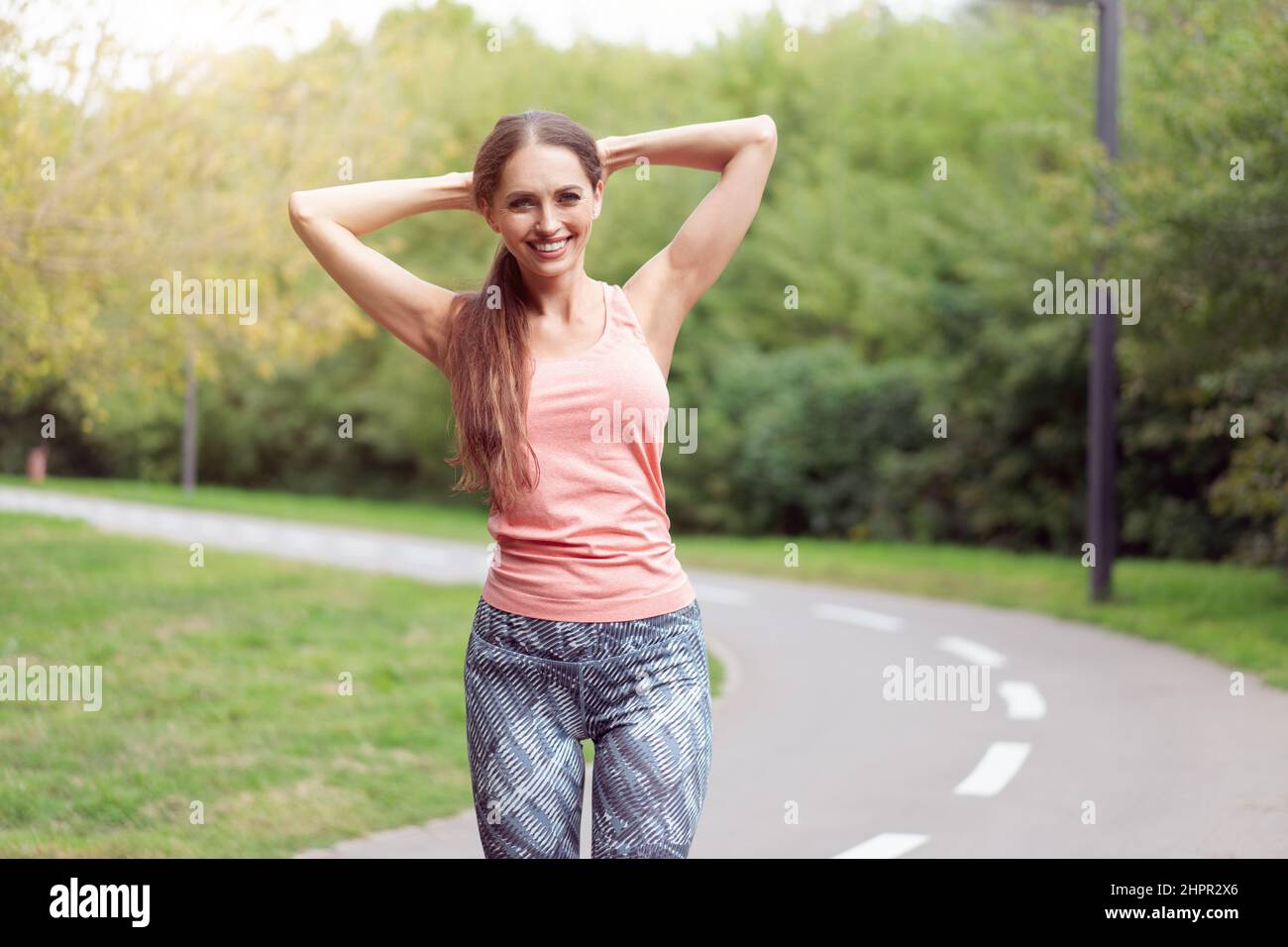 Woman runner stretching arms before running summer park Middle age ...