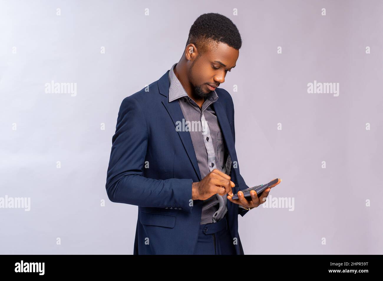 Young African man in a costume calculating something on a white ...
