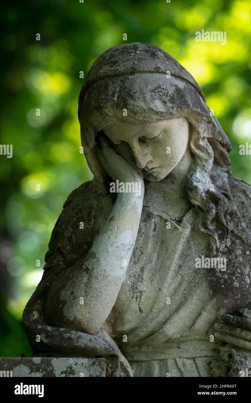 An ancient stone statue of sad and desperate woman on tomb as a symbol ...