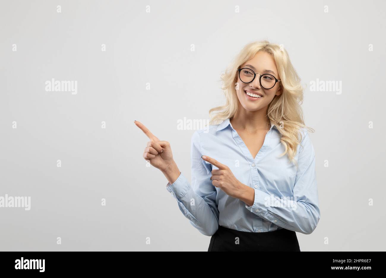 Happy lady entrepreneur in formal wear pointing aside at empty space ...