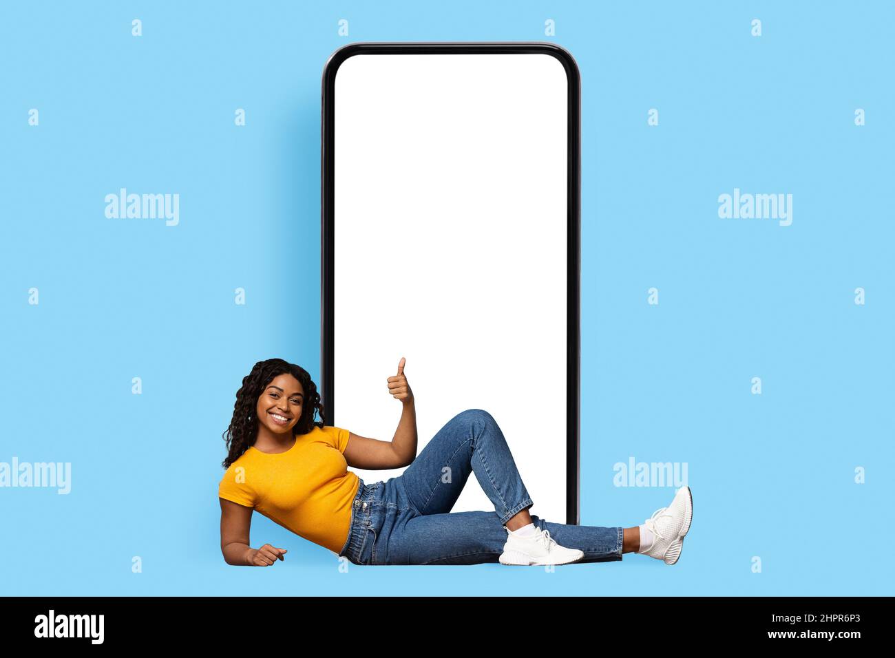 Cheerful black lady chilling by huge smartphone with blank screen Stock ...