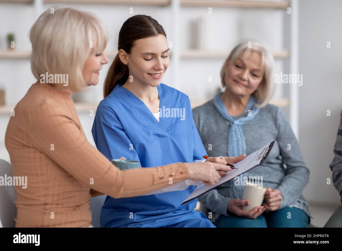 Pretty young nurse questioning senior ladies at nursing home Stock ...