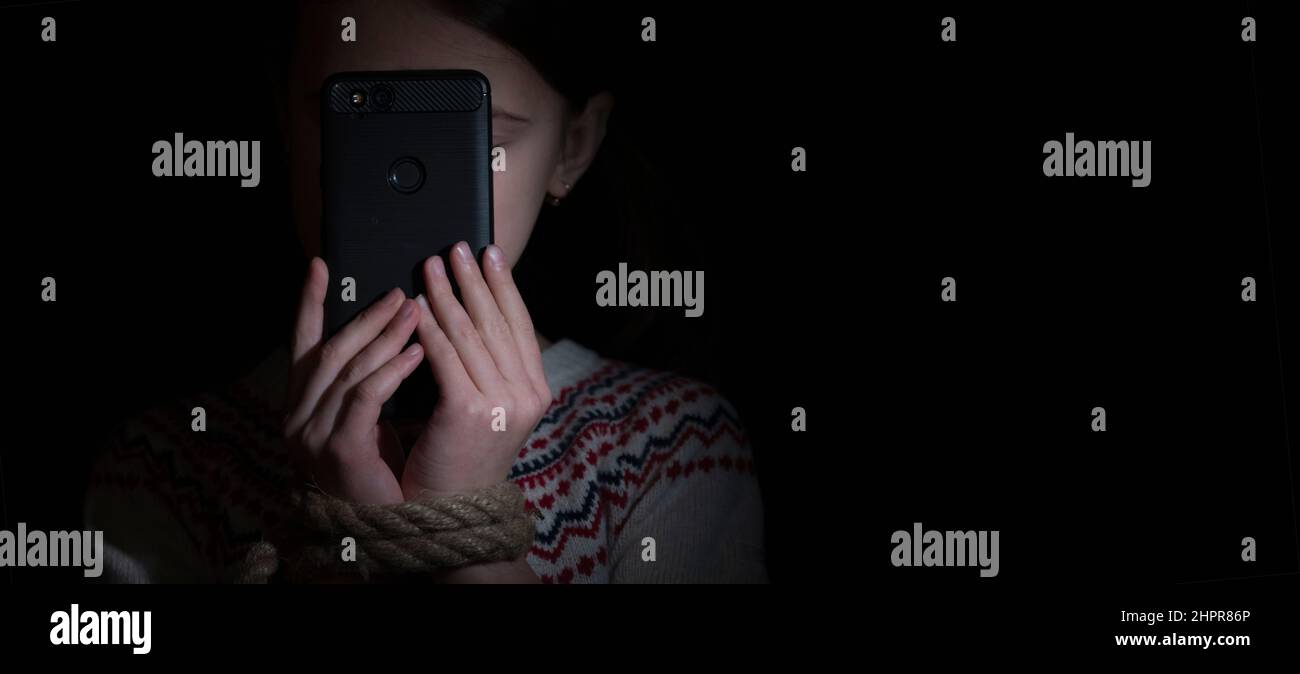 Internet addiction. Portrait of young girl tied with rope and holds ...