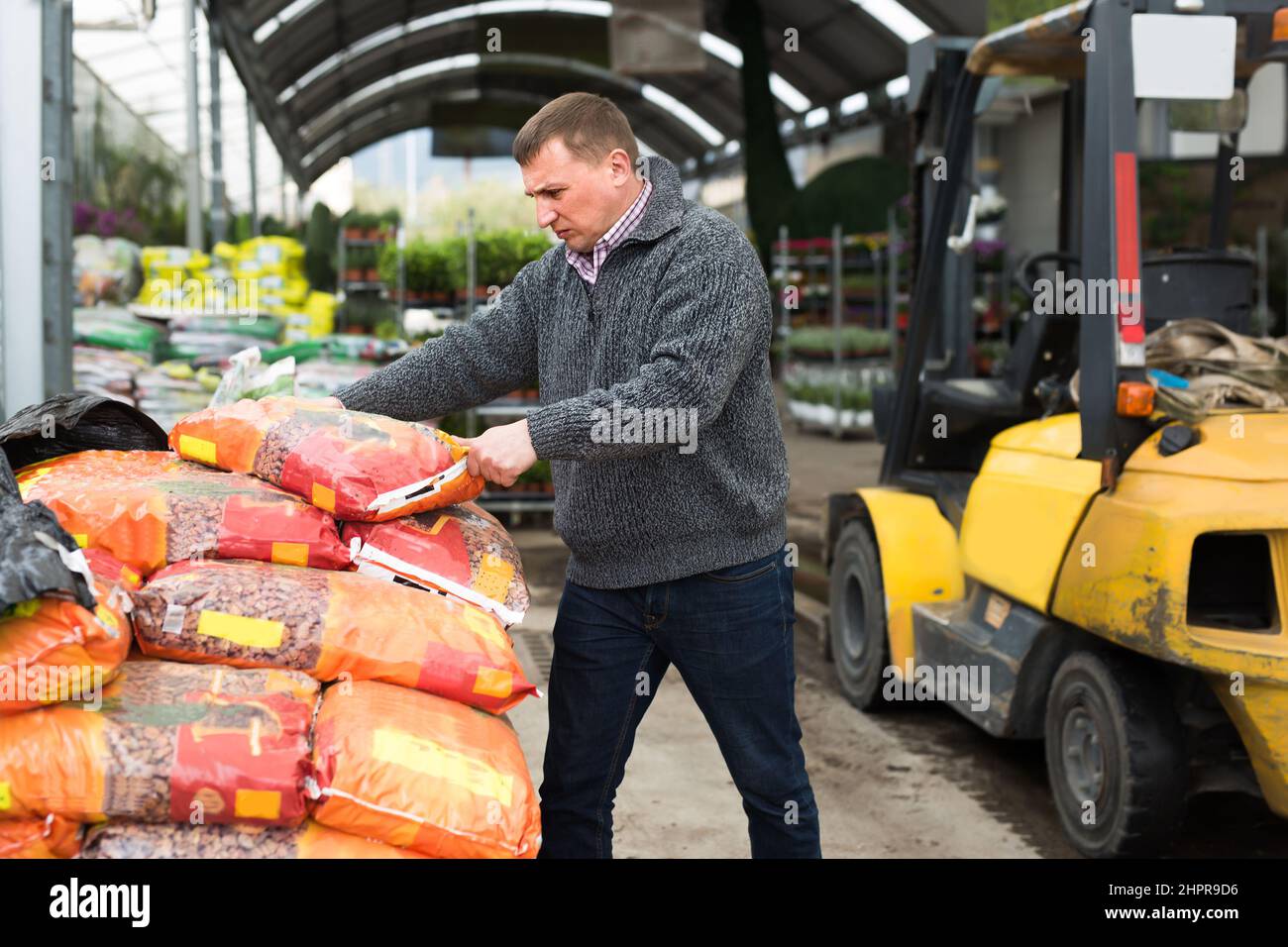 Focused man working in warehouse at garden store Stock Photo - Alamy