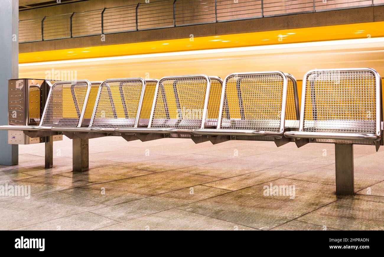 Yellow Train speeding in subway underground behind metal waiting ...