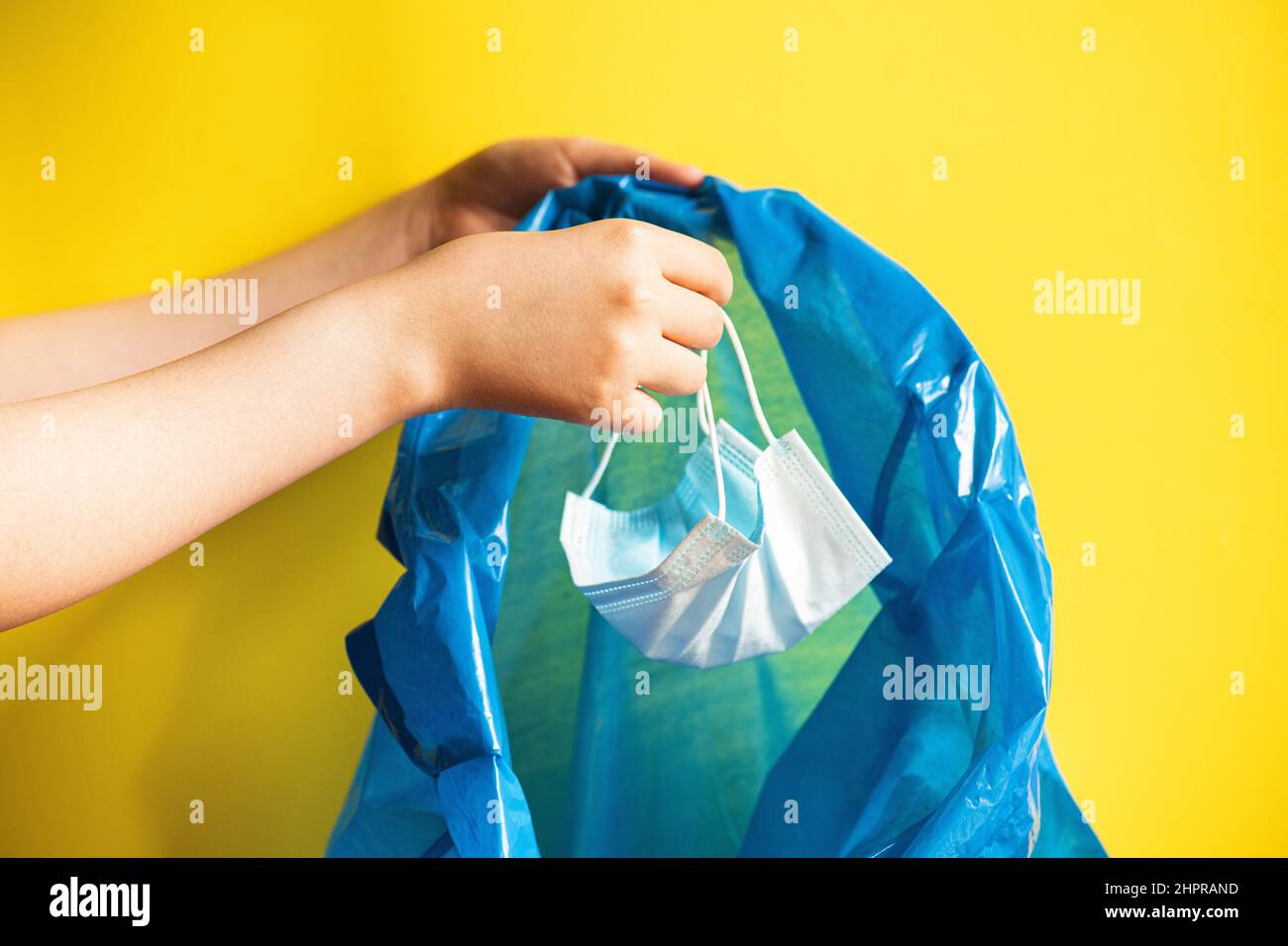 Cropped person's hand throw the mask in the trash bag. To show lift a ...